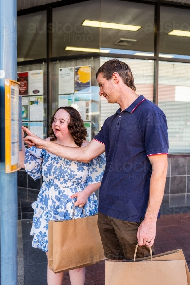 Image of Disability worker NDIS provider helping young woman check bus ...