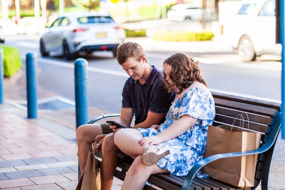 Image of Disability worker sitting at bus stop checking timetables on ...