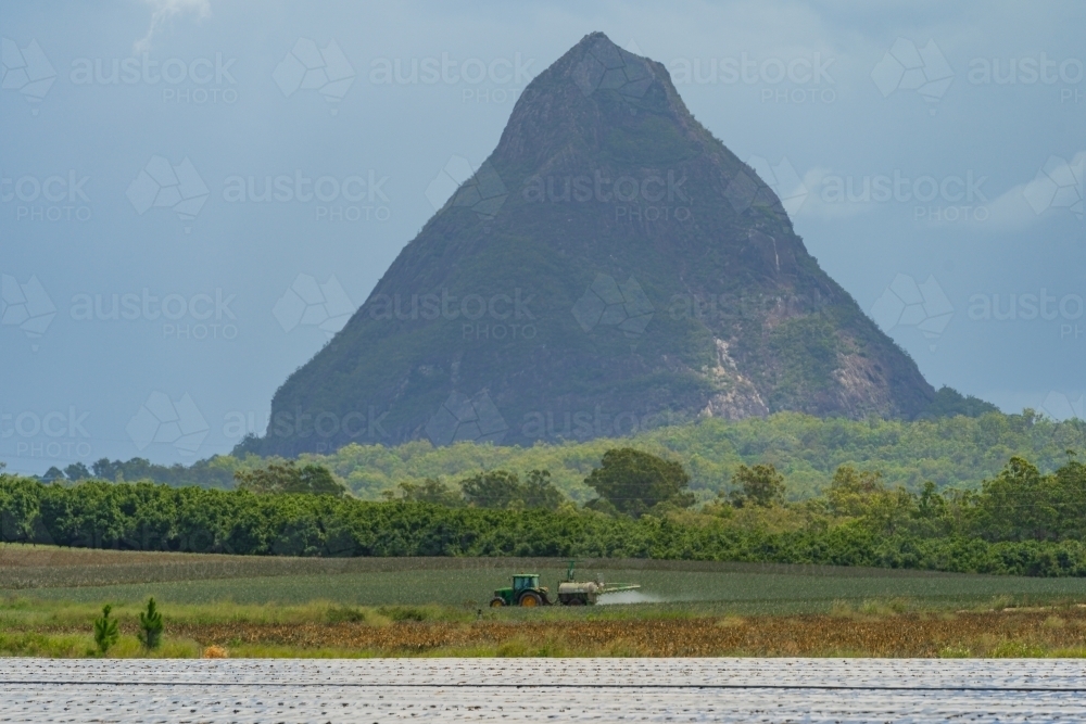 Image of Distant view of a large triangular mountain with a tractor ...