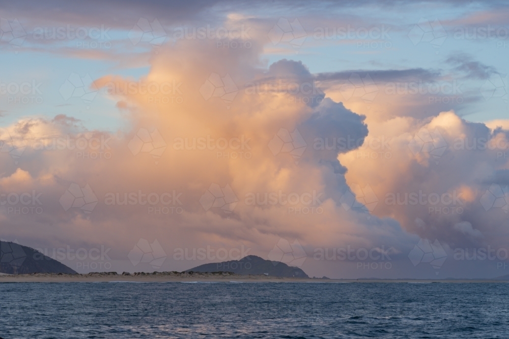 Image of Distant view of large colourful storm clouds over a coastal ...