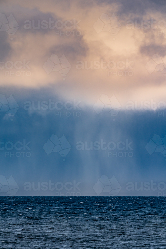 Image of Distant view of rain falling from clouds in a dark sky over a ...