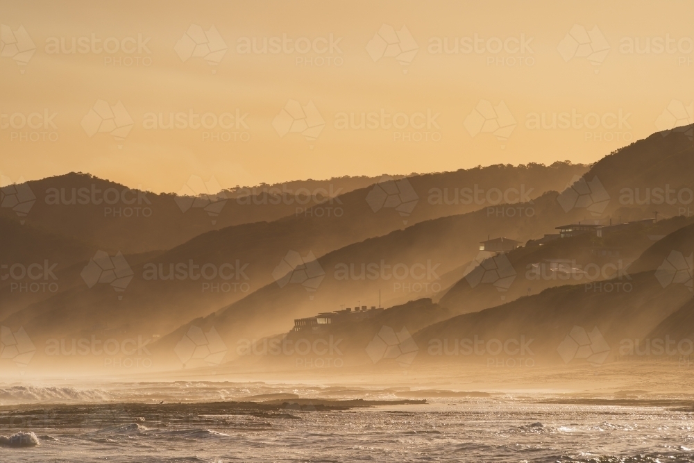 Image of Distant view of sea mist rolling up over coastal hills above ...
