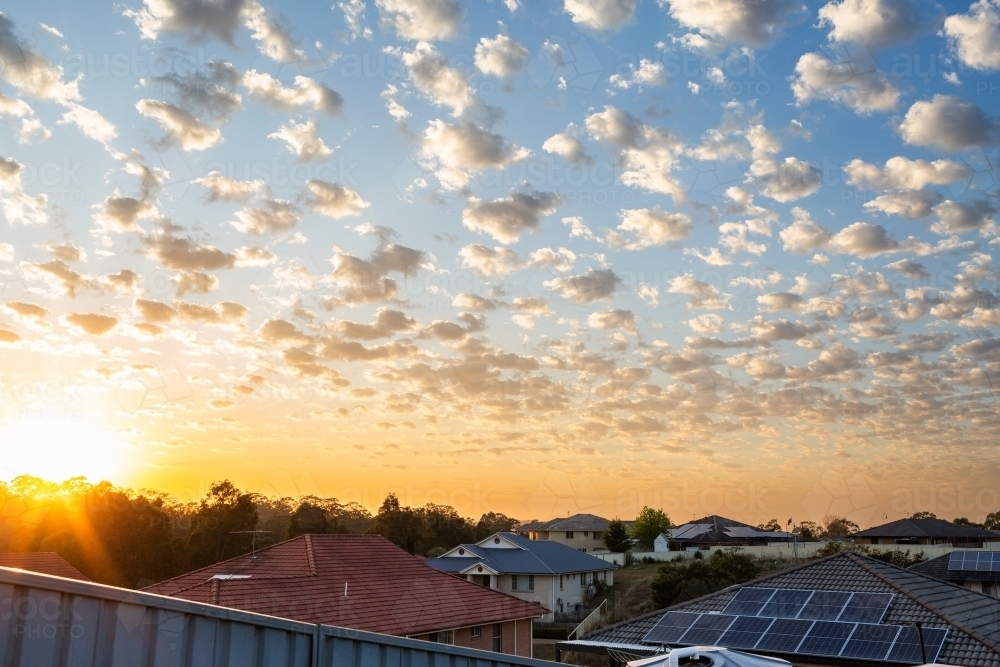 Image of Dotted clouds and sunrise sky over suburban rooftops ...