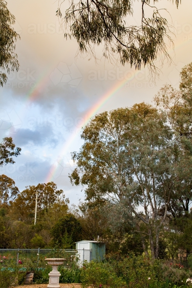 Image of Double rainbow over garden in backyard - Austockphoto