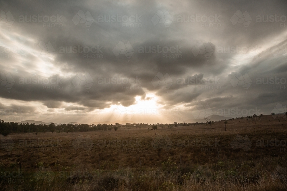 Image of dramatic skies with dark clouds and sun shining through in ...