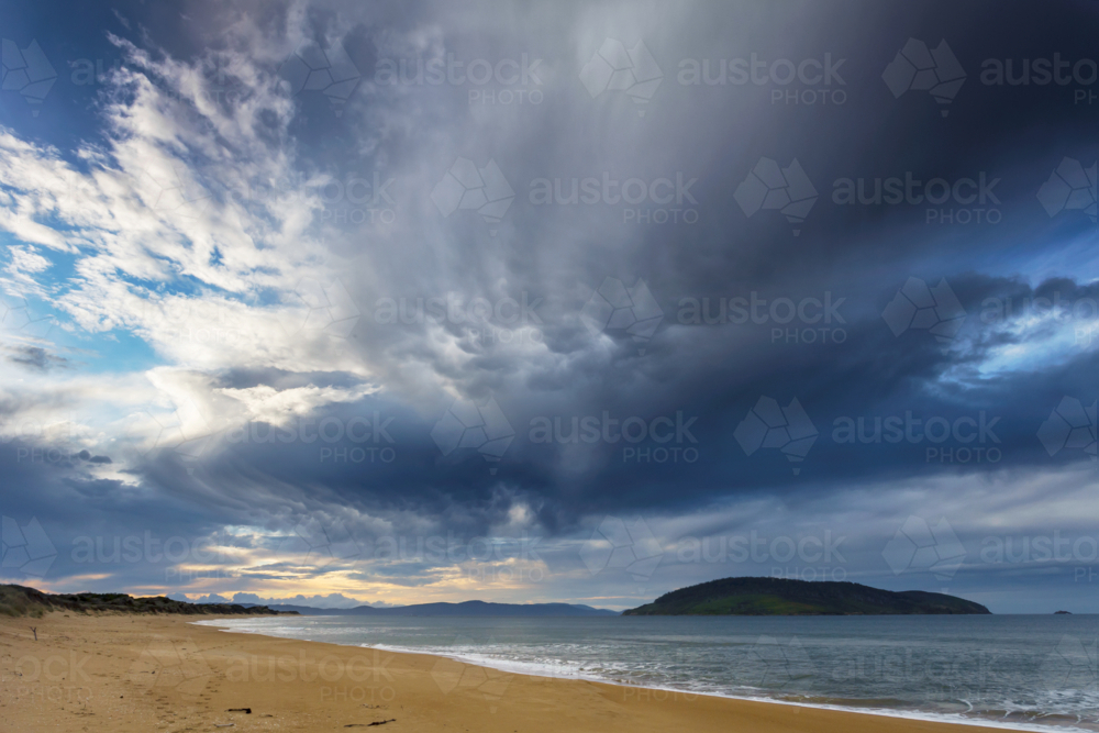 Image of Dramatic storm clouds build over a coastal island and sandy beach - Austockphoto