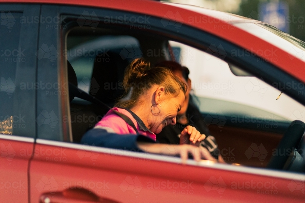 Image of driver of a parked car having a laugh with the window down ...