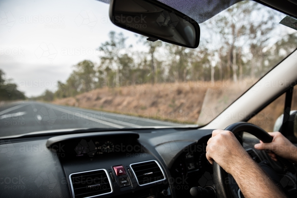 Image of driver with hands on the wheel looking at an empty highway ...
