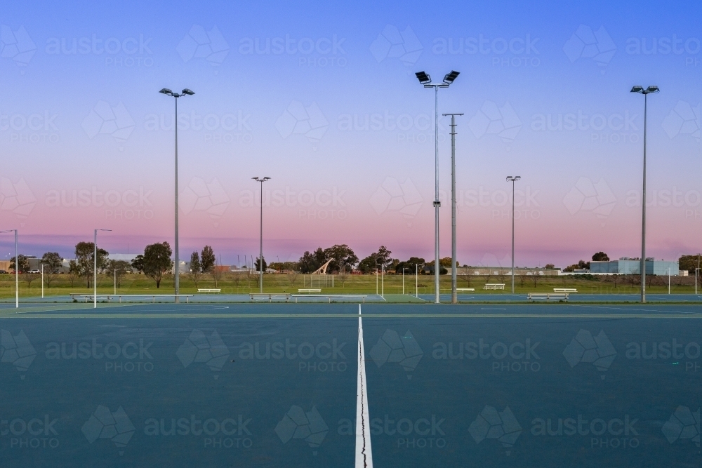 Image of Dusk sky behind empty netball courts in sports park - Austockphoto