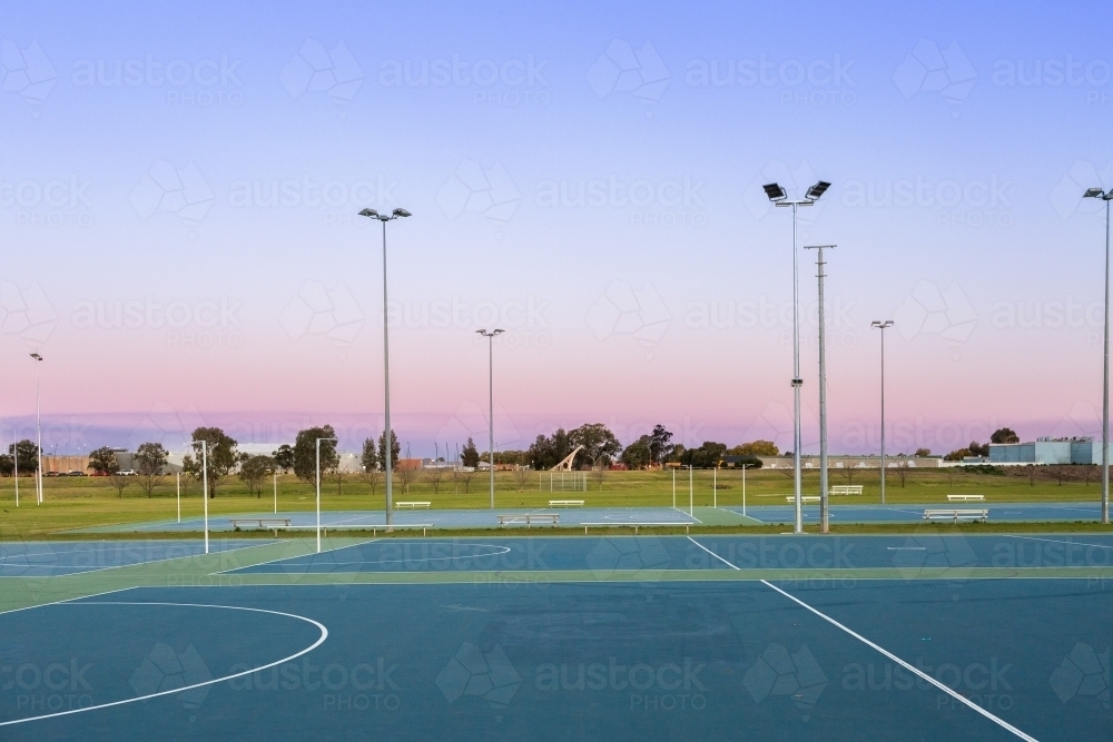 Image of Dusk sky behind empty netball courts in sports park - Austockphoto