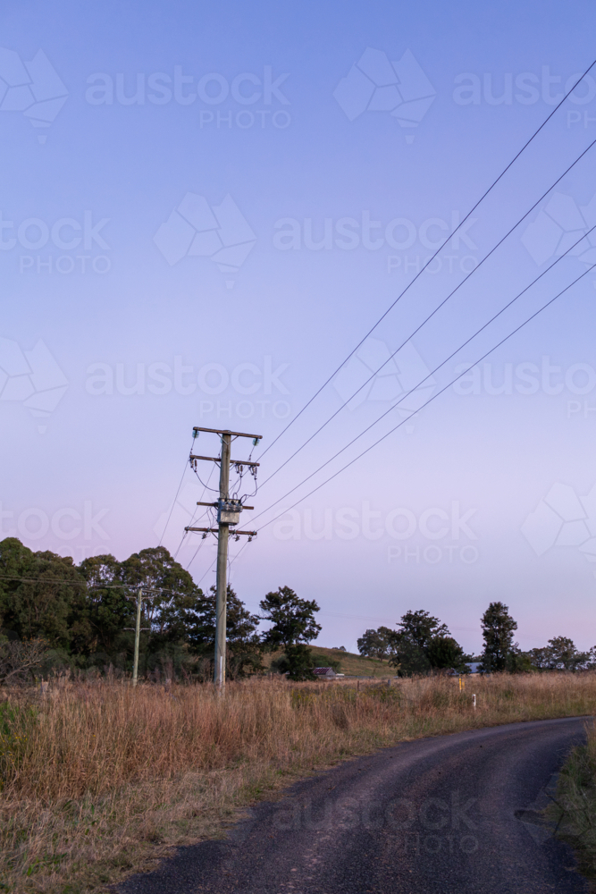 Image of dusk sky in country behind power pole and wires over narrow ...
