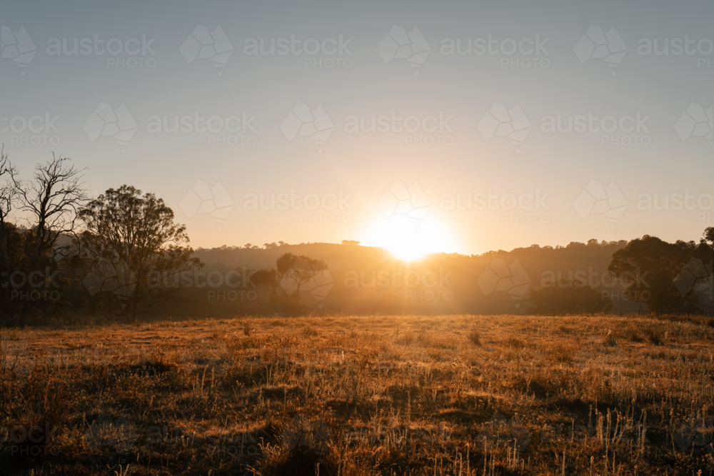Image of Early morning sunrise emerging over distant hills in the ...