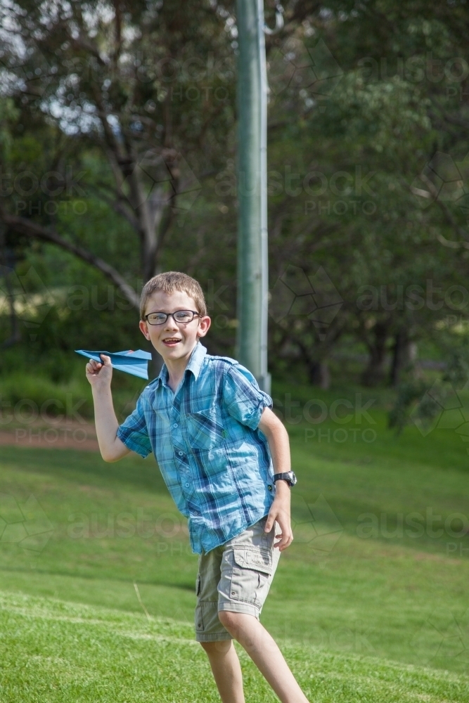 Image of Eight year old boy flying a paper plane outside - Austockphoto