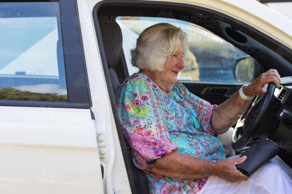Image of elderly female driver about to exit vehicle holding her purse ...