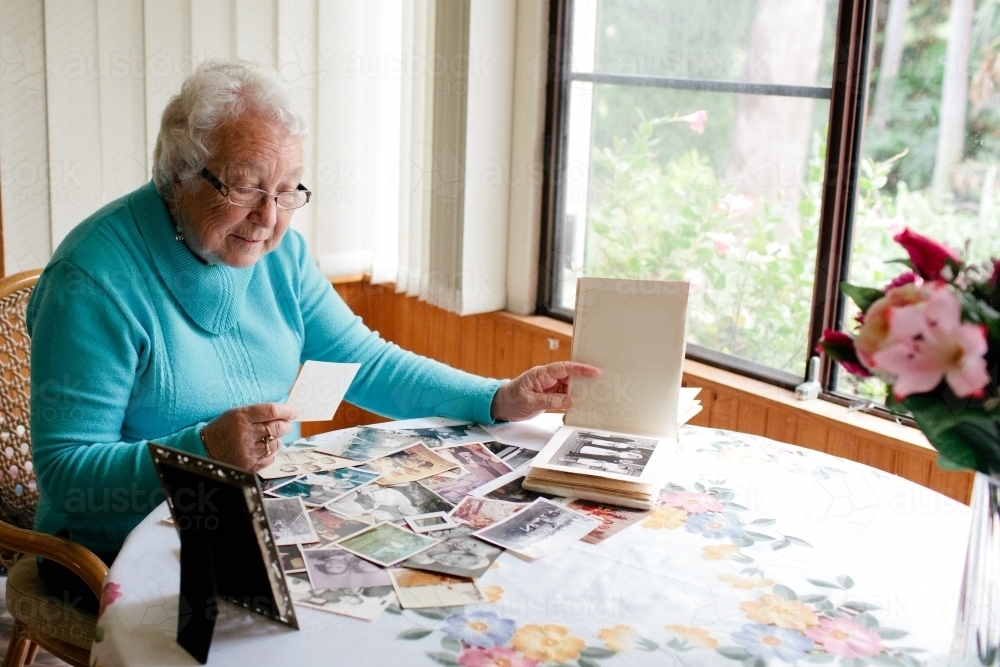 Image of Elderly lady browsing through photographs - Austockphoto