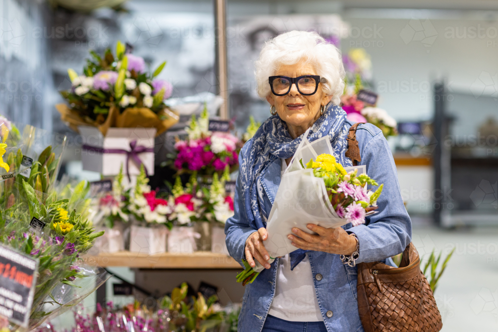 Image of elderly lady holding a wrapped bunch of flowers in a flower ...