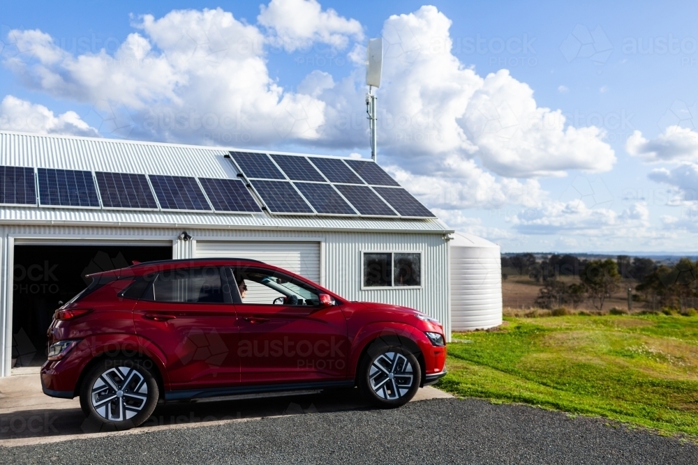 Image of electric vehicle red car near shed with solar panels and mini ...
