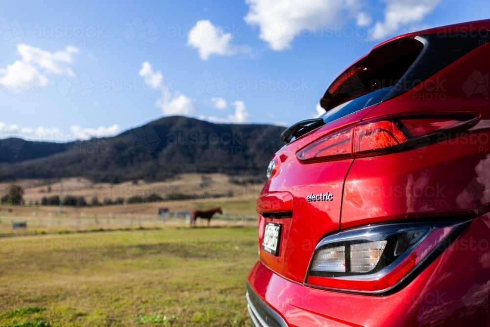 Image of Electric word in back of red electric vehicle car in rural ...
