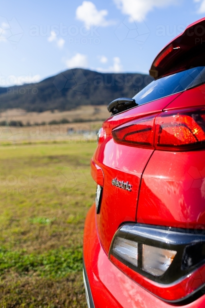 Image of Electric word in back of red electric vehicle car in rural ...