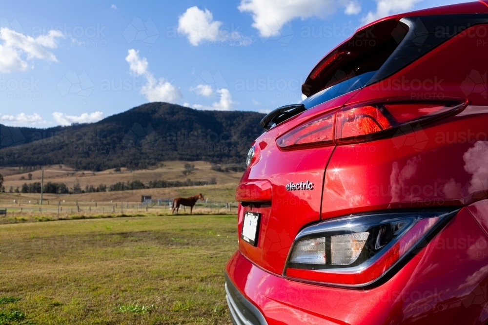 Image of Electric word in back of red electric vehicle car in rural ...