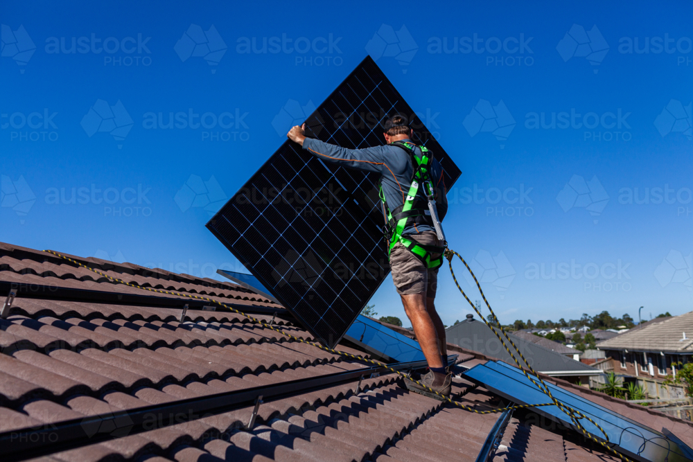Image of Electrician positioning bifacial solar panels on roof for ...