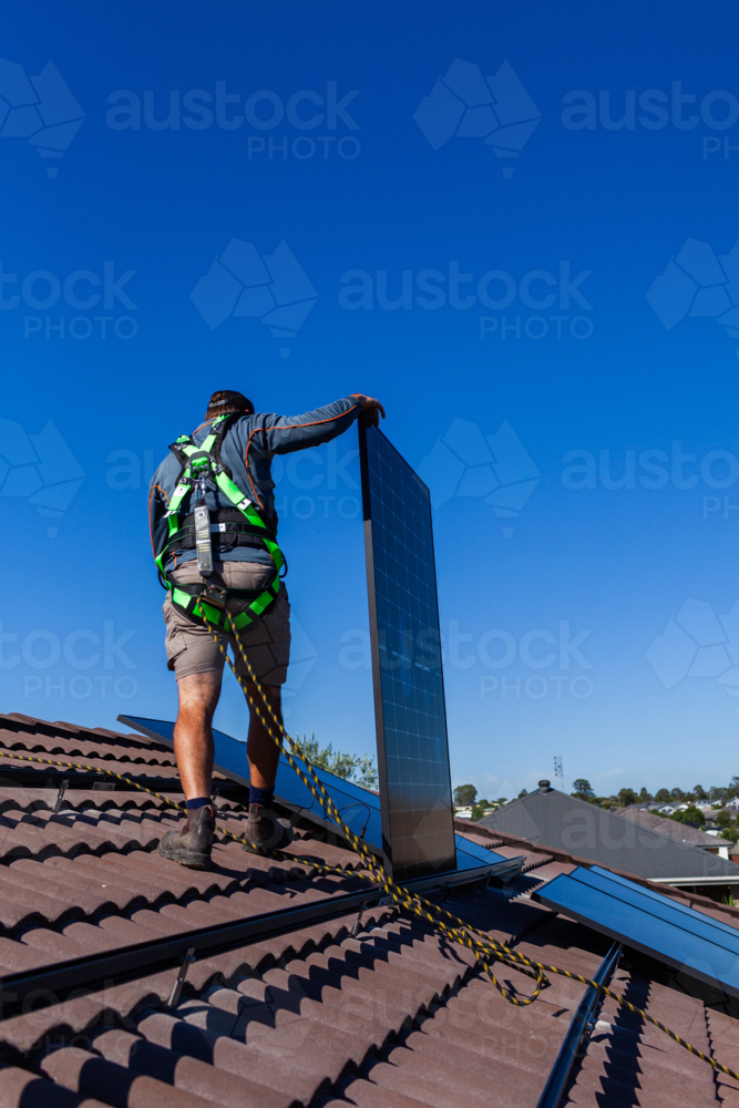 Image of Electrician positioning bifacial solar panels on roof for ...