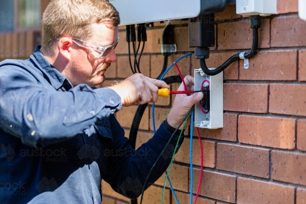 Image of Electrician screwing in switch and electronics for solar power ...