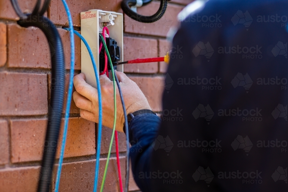 Image of Electrician screwing in switch and electronics for solar power ...