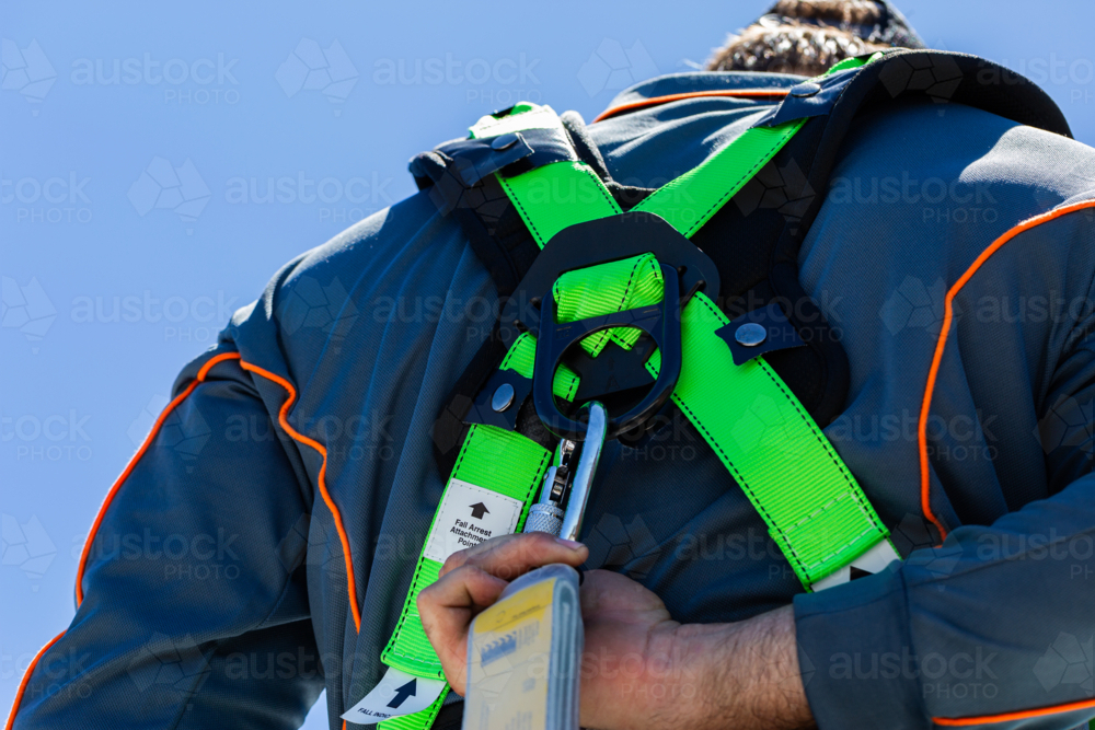 Image of Electrician tradie man clipping rope to safety harness during ...