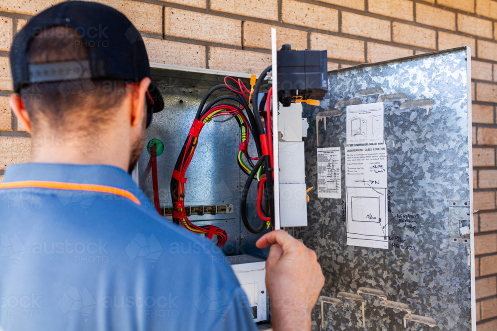 Image of Electrician tradie working on outside breaker box power box ...