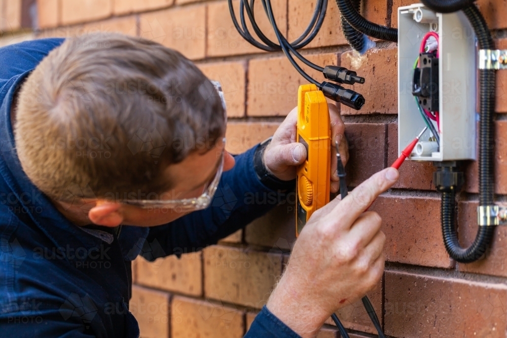 Image of Electrician using multimeter tool to check power in solar ...