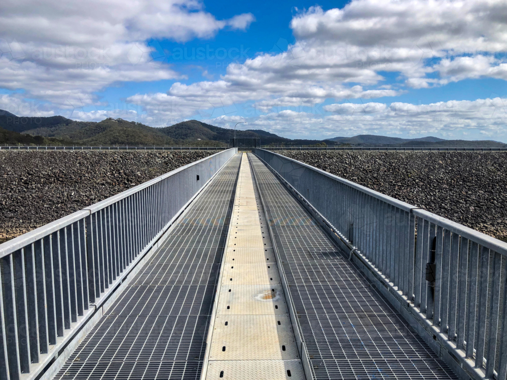 Image of Elevated metal walkway and dam wall. - Austockphoto