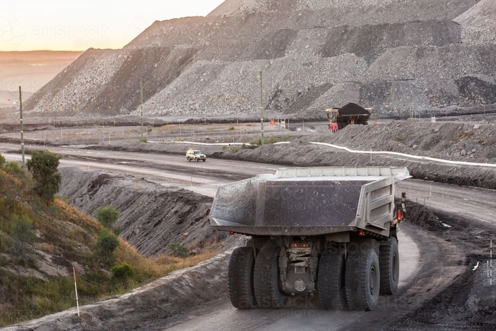 Image of Empty dump truck in coal mine with full truck in distance ...