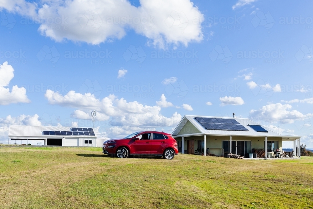 Image of EV car on farm in country, buildings in the background have ...