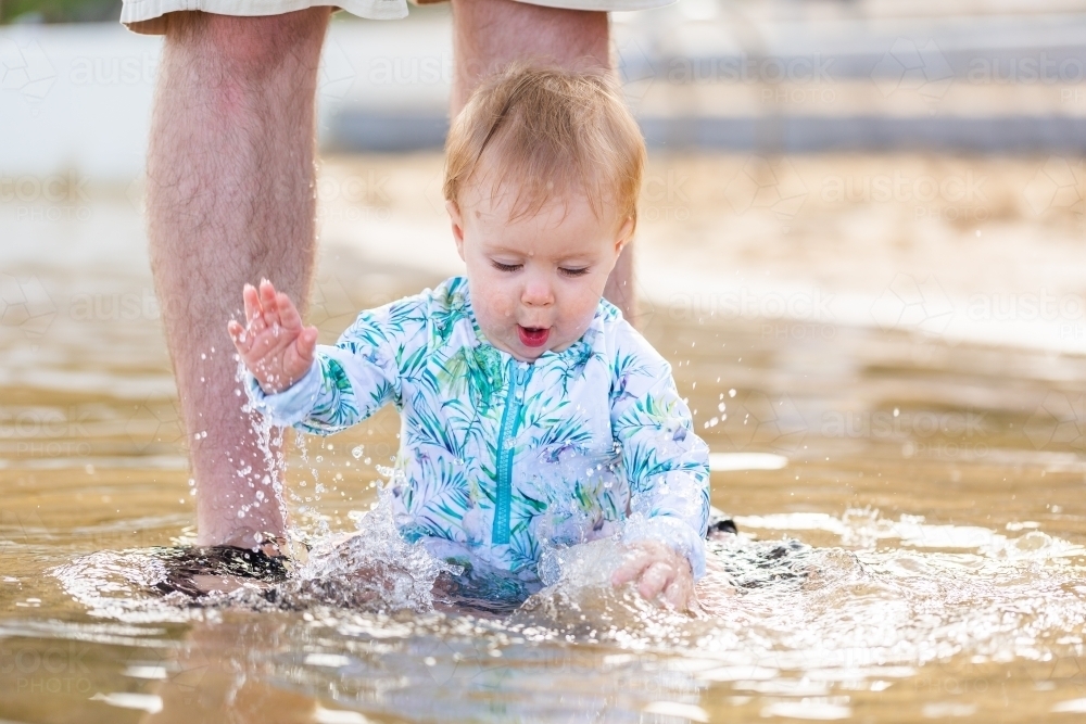 Image of Excited baby girl splashing in water at beach on holiday ...