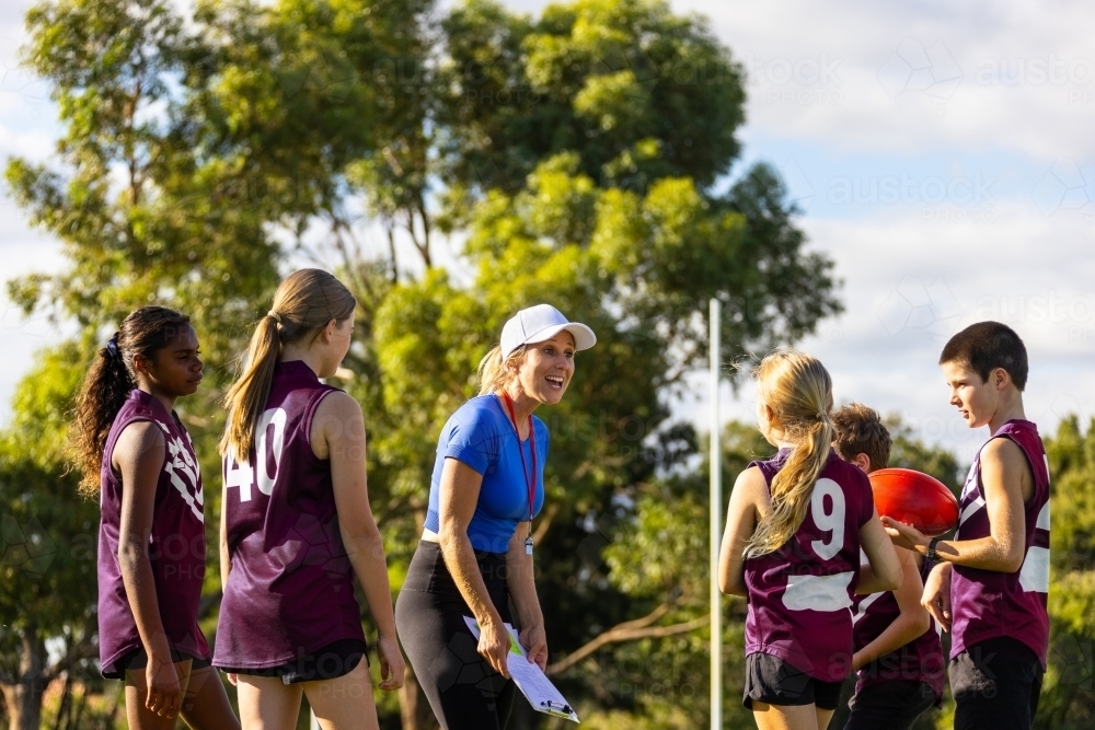 Image of excited lady giving a pep talk to the kids she is coaching at ...
