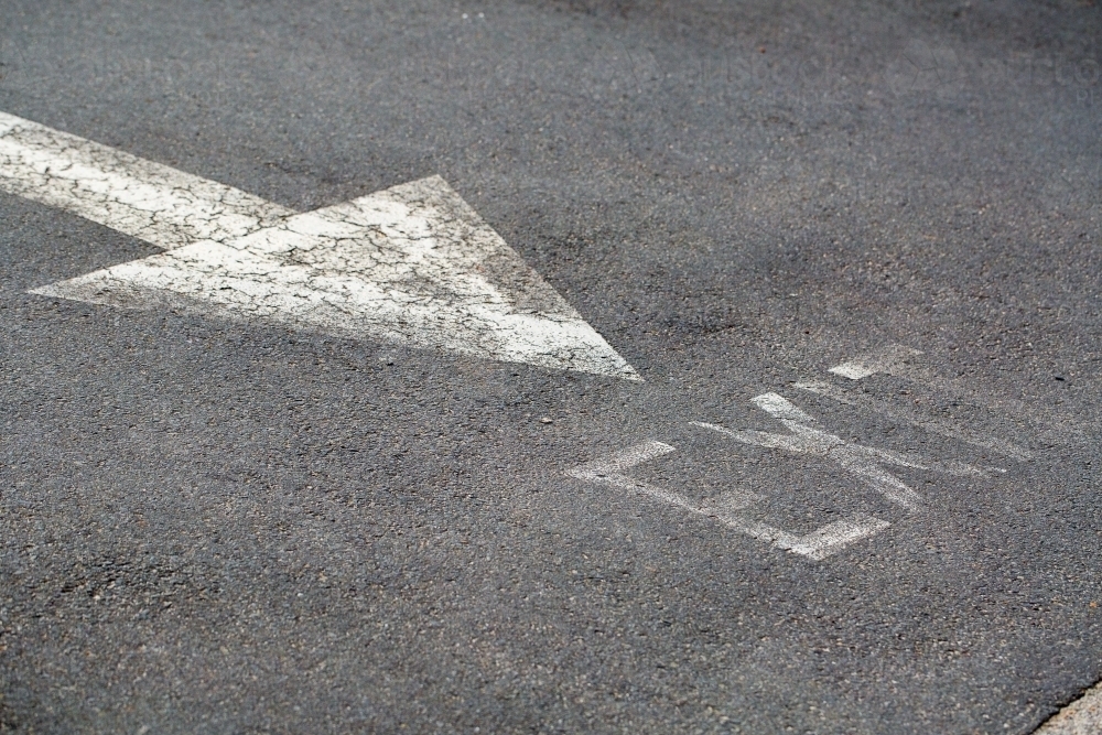 Image of Faded white arrow painted on bitumen road - Austockphoto