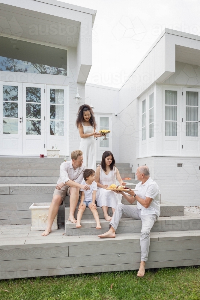 Image of Family eating snacks on backyard stairs - Austockphoto