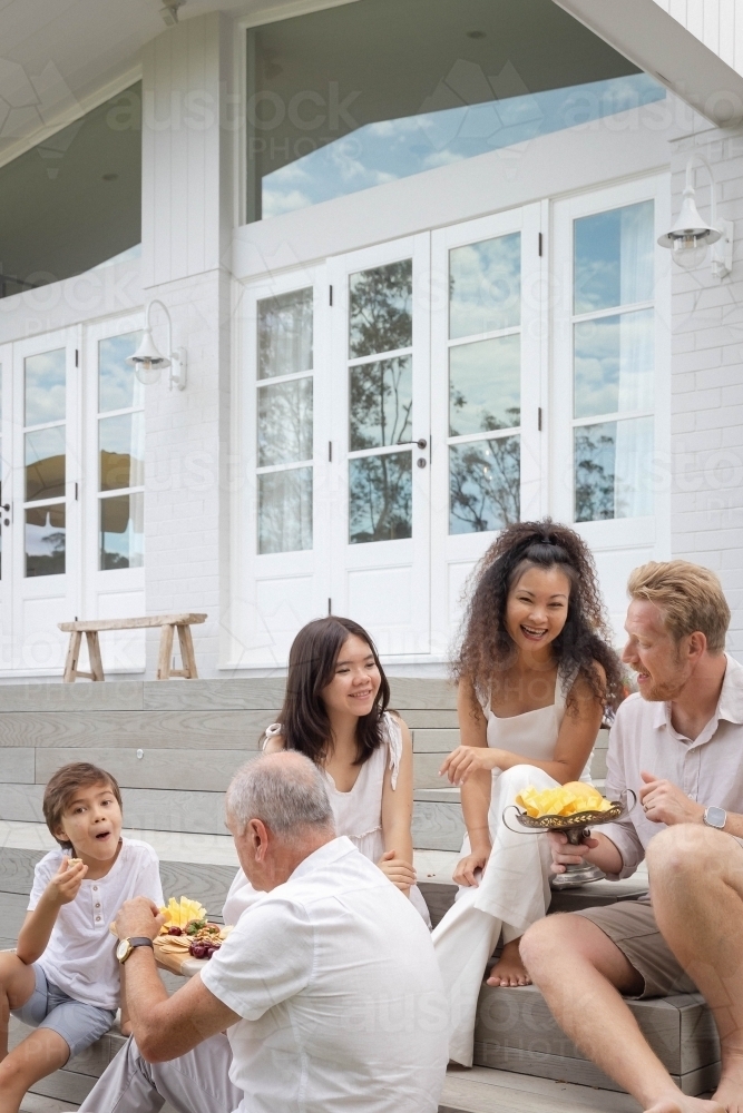 Image of Family eating snacks on backyard stairs - Austockphoto