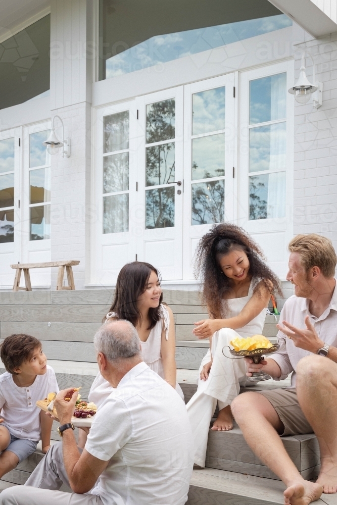 Image of Family eating snacks on backyard stairs - Austockphoto
