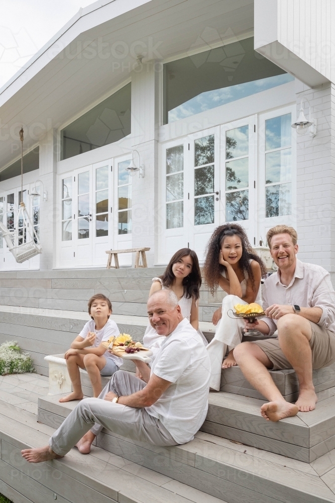 Image of Family eating snacks on backyard stairs - Austockphoto
