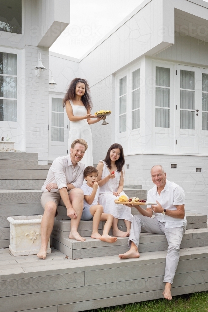 Image of Family eating snacks on backyard stairs - Austockphoto