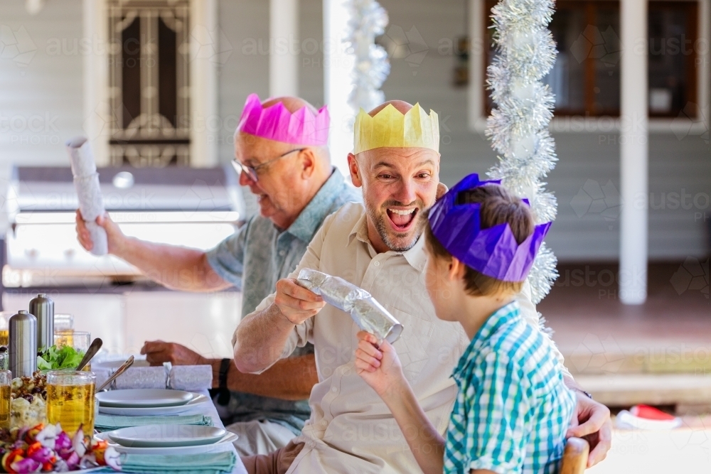 Image of Family laughing and cracking Christmas crackers together at ...