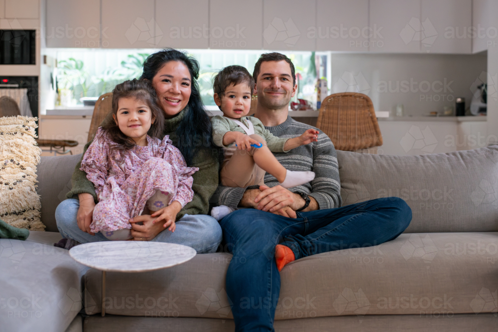 Image of Family of Four Sitting Together on Couch in Living Room ...