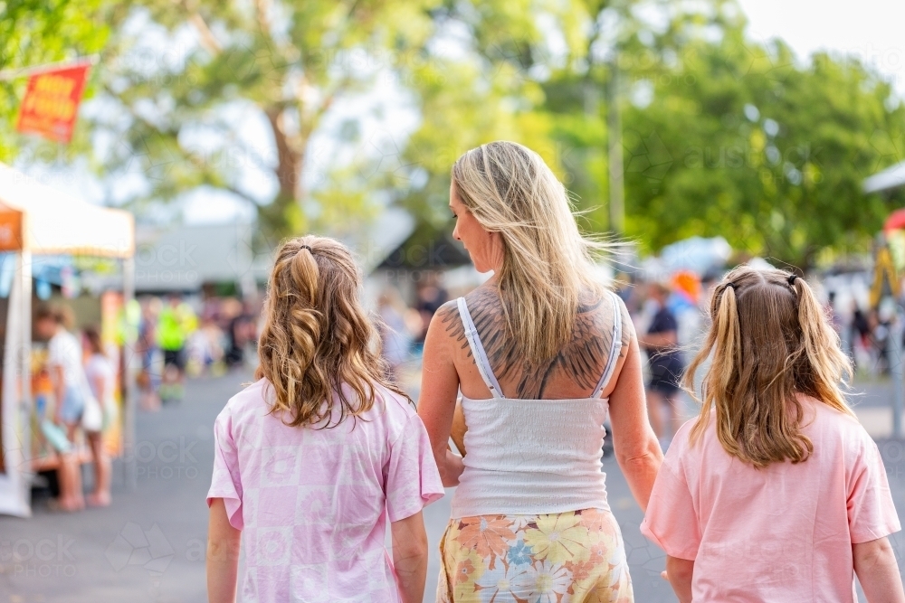 Image of Family of three walking through crowds at local public event ...