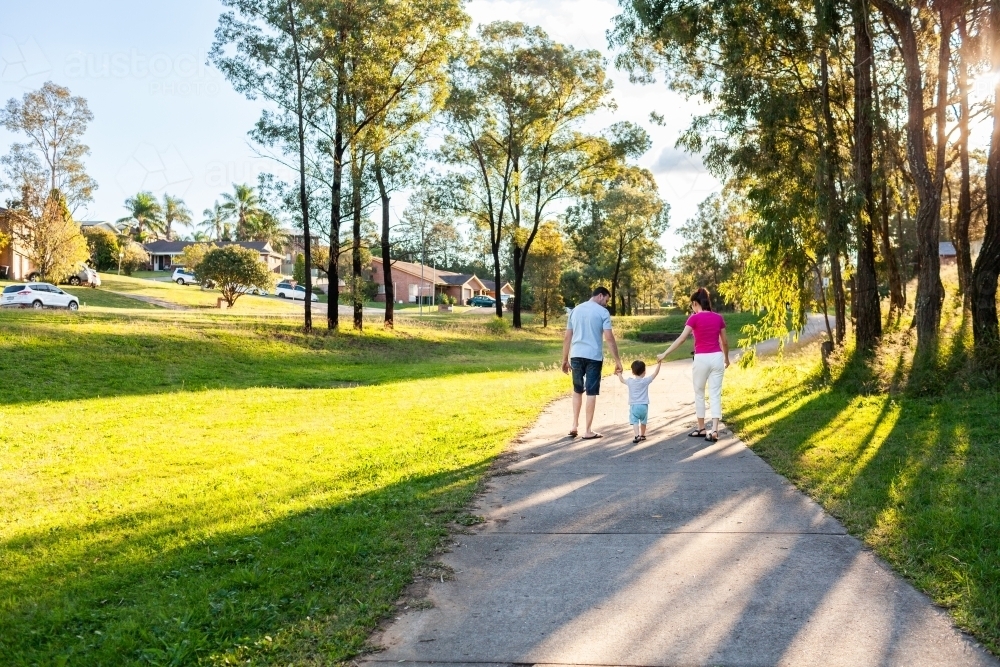 Image of Family of three with toddler on suburban walk in afternoon ...