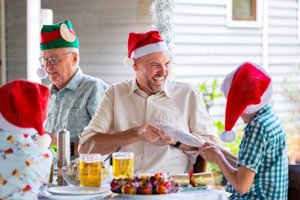 Image of Family popping Christmas crackers at Christmas lunch table dad ...