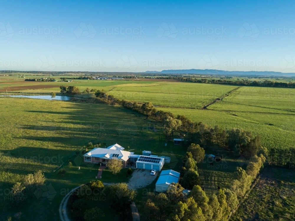 Image of Farm house in green paddock with solar panels on shed roof ...