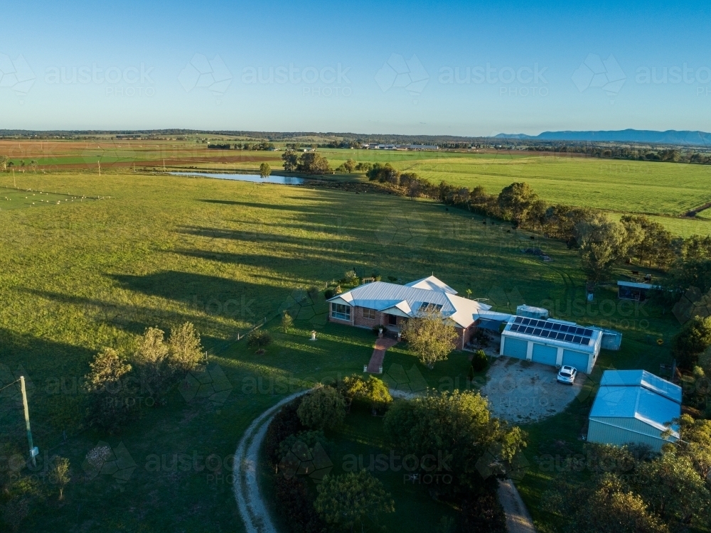 Image of Farm house in green paddock with solar panels on shed roof ...
