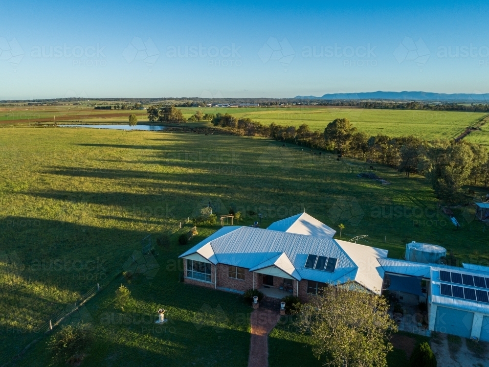 Image of Farm house in green paddock with solar panels on shed roof ...